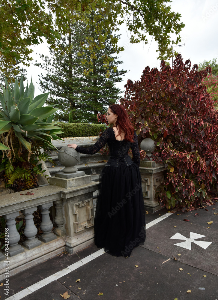 portrait of pretty female model with red hair wearing glamorous gothic ...