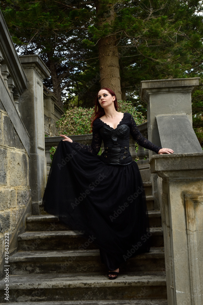 portrait of pretty female model with red hair wearing glamorous gothic ...