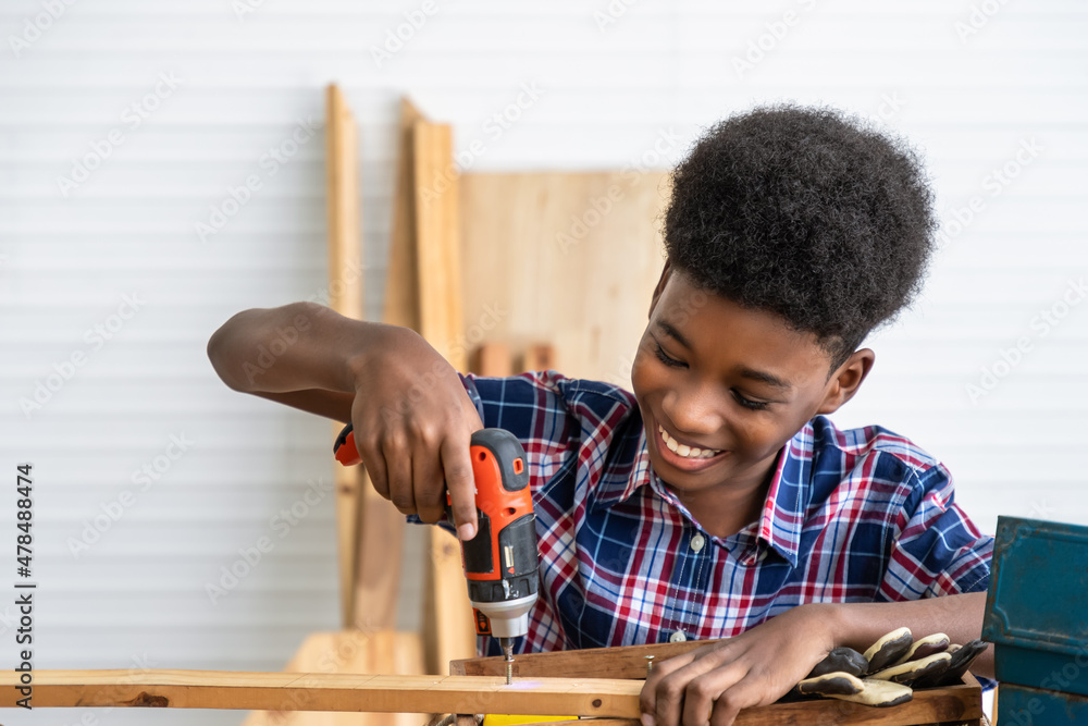 Concentrated African black boy child kid carpenter drilling hole in ...