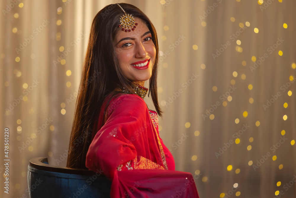 Young girl looking back at camera with smile while sitting on chair ...