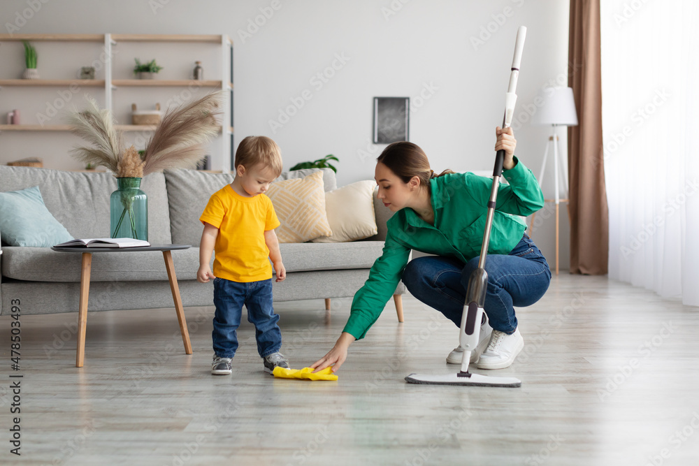 Little kid boy watching her mother mopping the floor after him. Woman ...