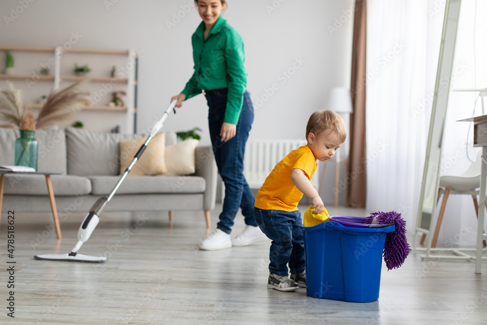 Little helper. Adorable toddler boy helping mom cleaning at home, kid ...