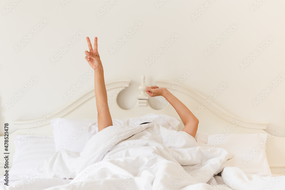 Woman in bed under the blanket stretching hand after waking up. Stock ...