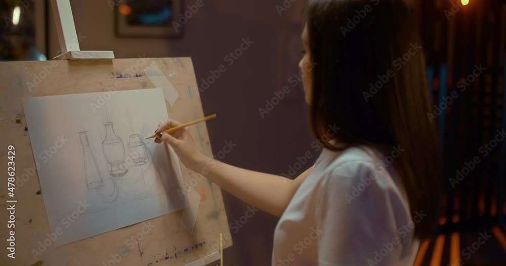 Girl draws with a pencil, graphics lesson. Girl observes the ...