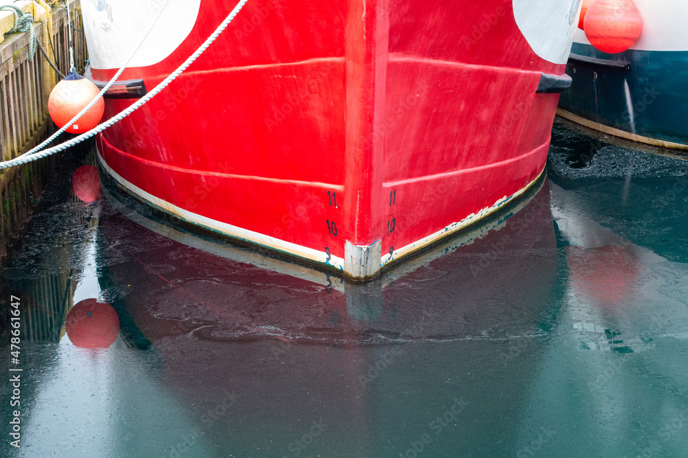A vibrant red metal ship with black and white waterline measurement ...