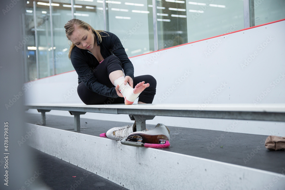 Female figure skater bandaging ankle in skating rink Stock Photo ...