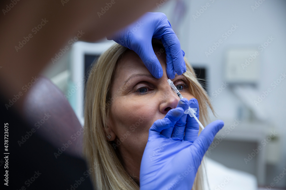 Technician giving woman botox injection corner of eye Stock Photo ...