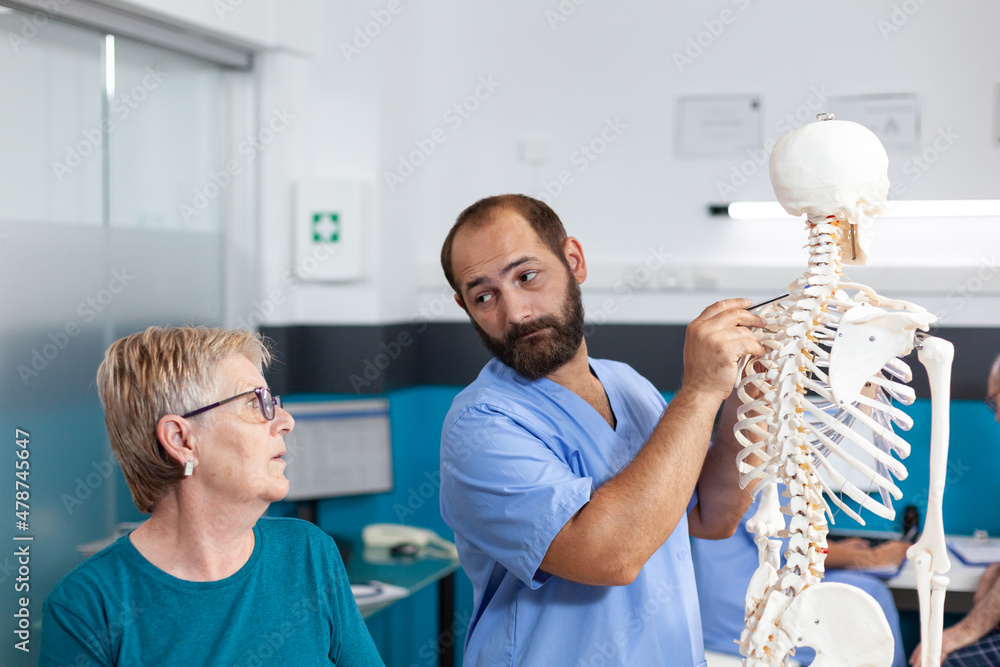 Woman and nurse looking at spinal cord on human skeleton for ...
