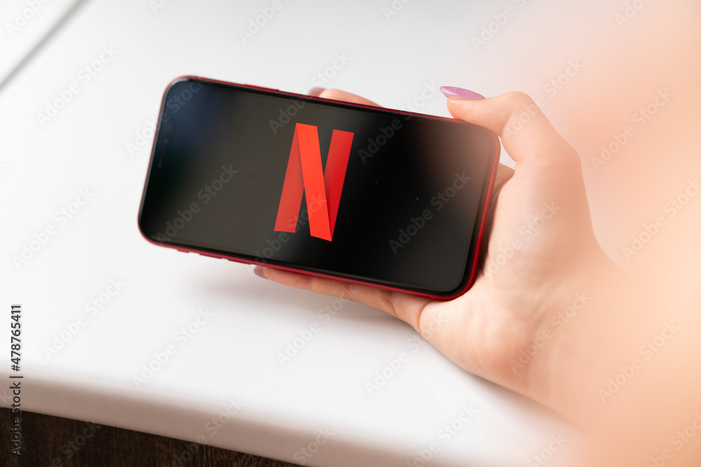 A woman uses the Netflix app on her smartphone screen. Netflix is the ...