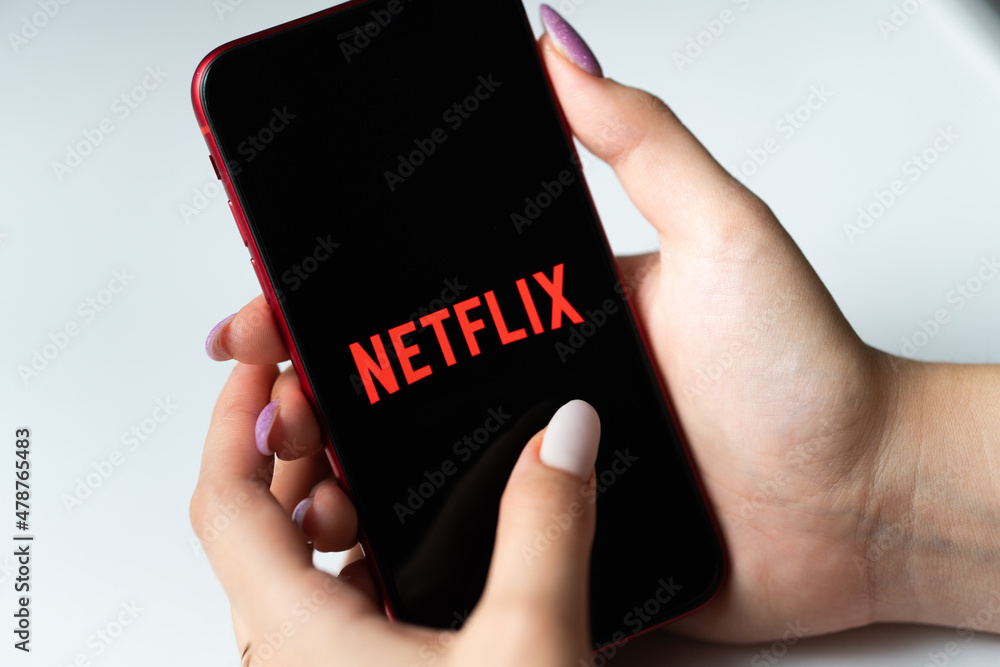A woman uses the Netflix app on her smartphone screen. Netflix is the ...