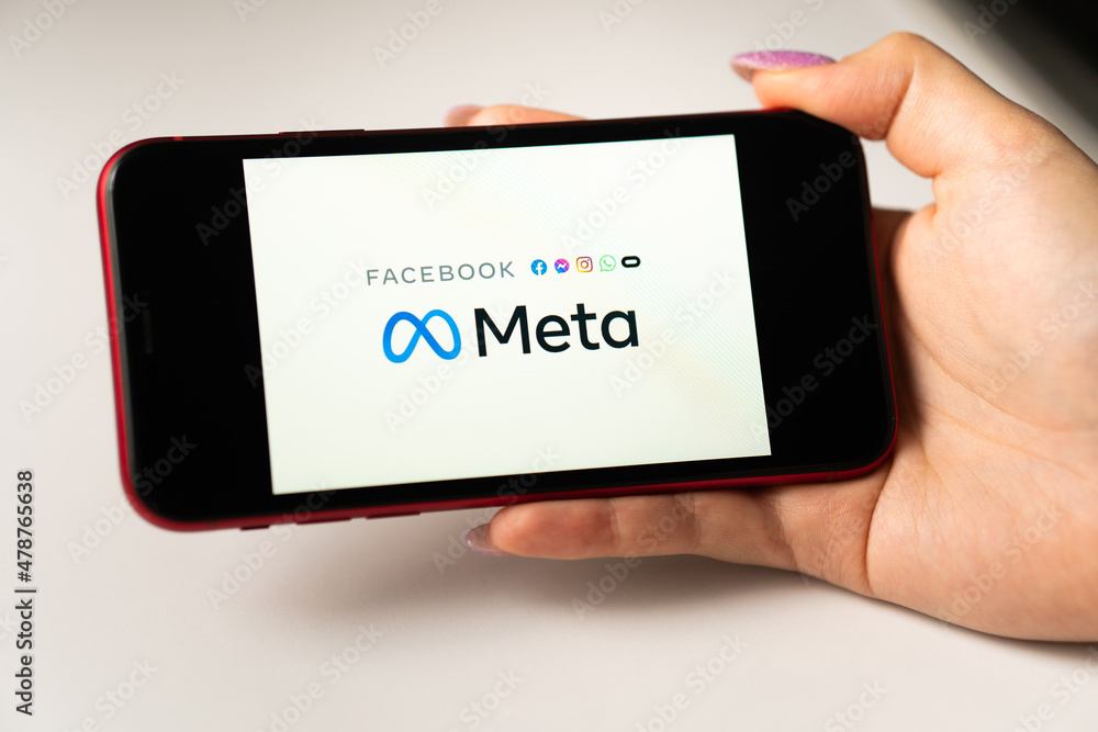 META logo on smartphone being held in hand in front of phone with ...