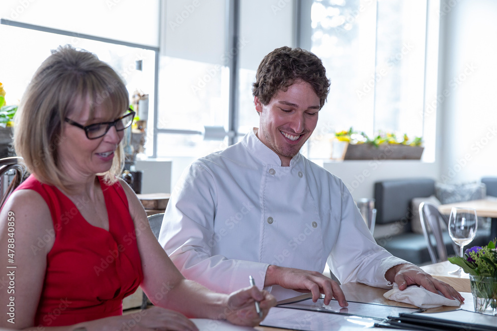 Bistro owner and chef planning menu at table 스톡 사진 | Adobe Stock
