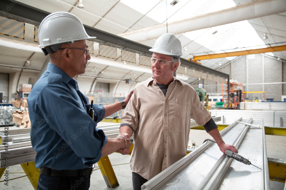 Workers handshaking in manufacturing plant Stock Photo | Adobe Stock