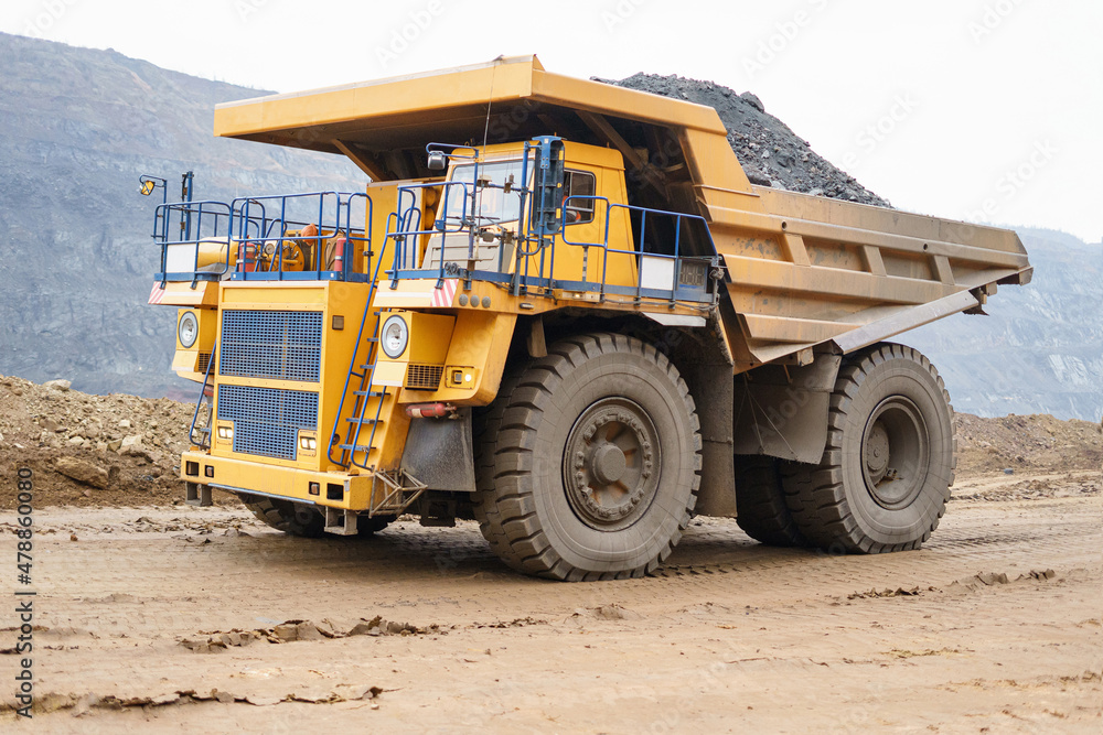 A large open-pit dump truck rides in an open-pit ore quarry. Part of ...
