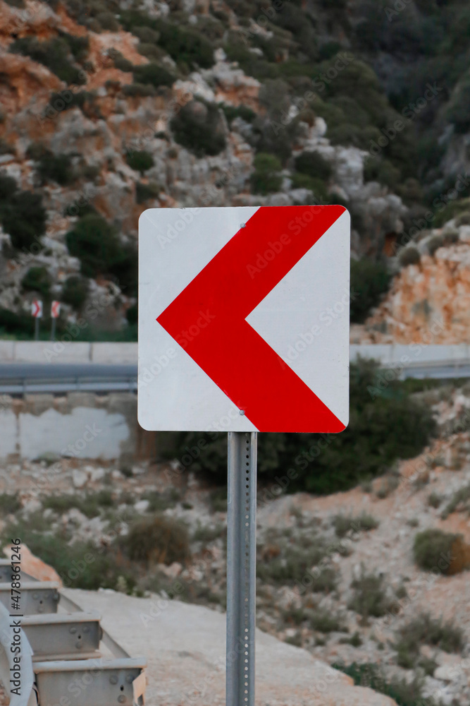 Left turn sign: Road signs warn of a sharp turn on a narrow, rocky road ...