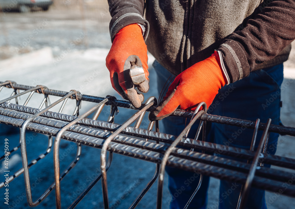 Details of construction worker - hands securing steel bars with wire ...
