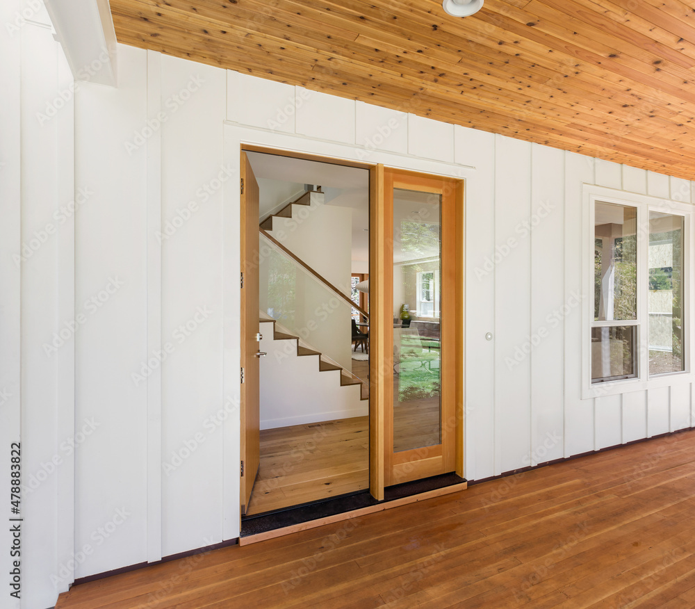 Front door to new home. Covered porch with hardwood floor, ceiling, and ...