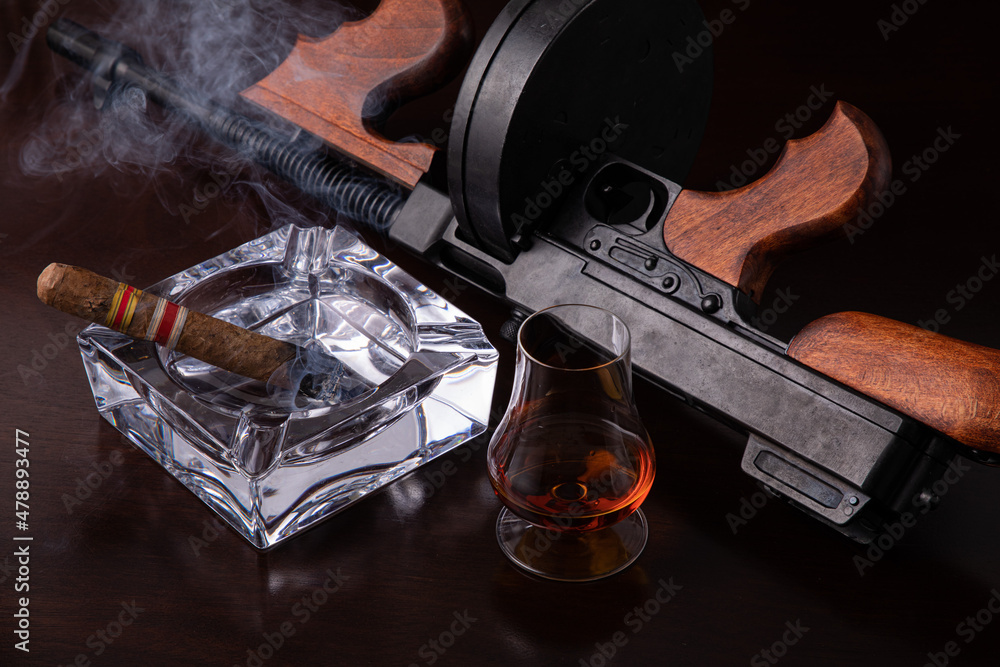 Vintage Thompson submachine gun on a dark brown table with a cigar and ...