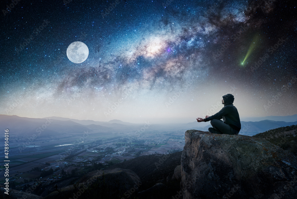 person sitting on the top of the mountain outdoors meditating or ...