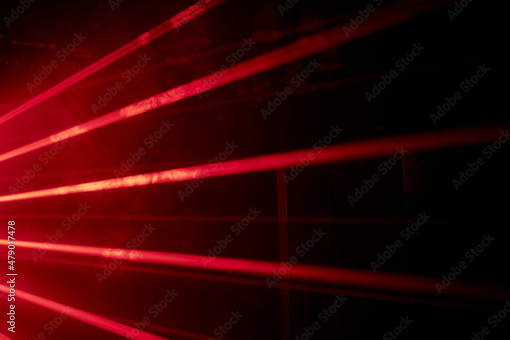 Bright red neon laser lights illuminate the darkness creating lines and ...