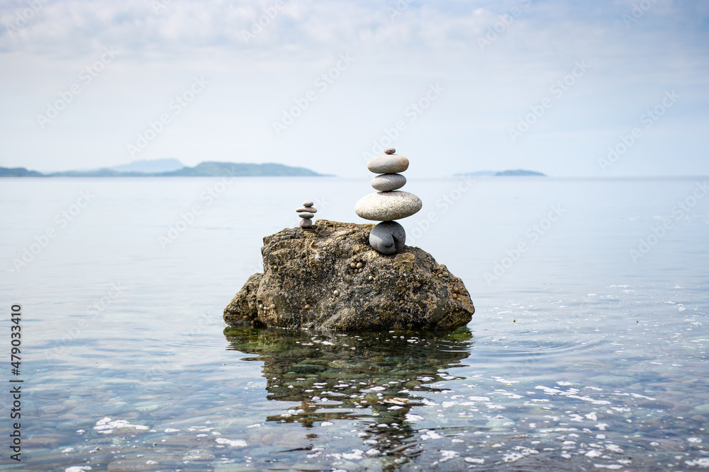 Pebbles balanced upon a rock in the sea - ying and yang balance ...