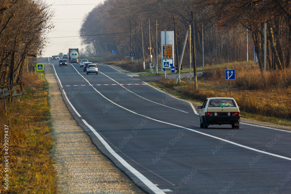Road lined with autumn trees. Cross hatching road marks line the centre ...