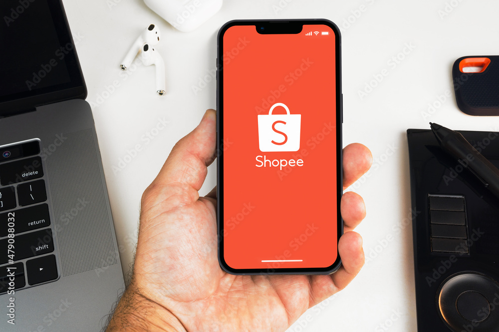 Male hand holding a smartphone with Shopee app on the screen. Office ...