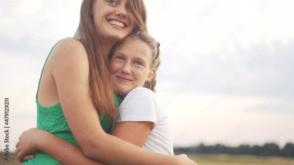 two sisters of a teenager hugging in nature in the park. happy family ...