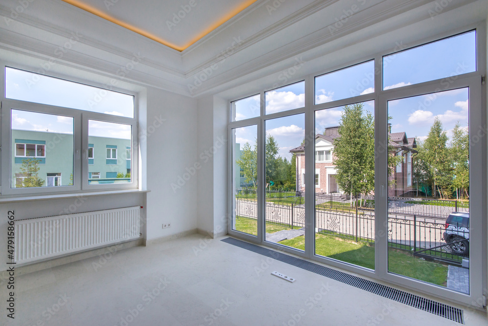An empty, bright, unfurnished living room with a high ceiling and a ...
