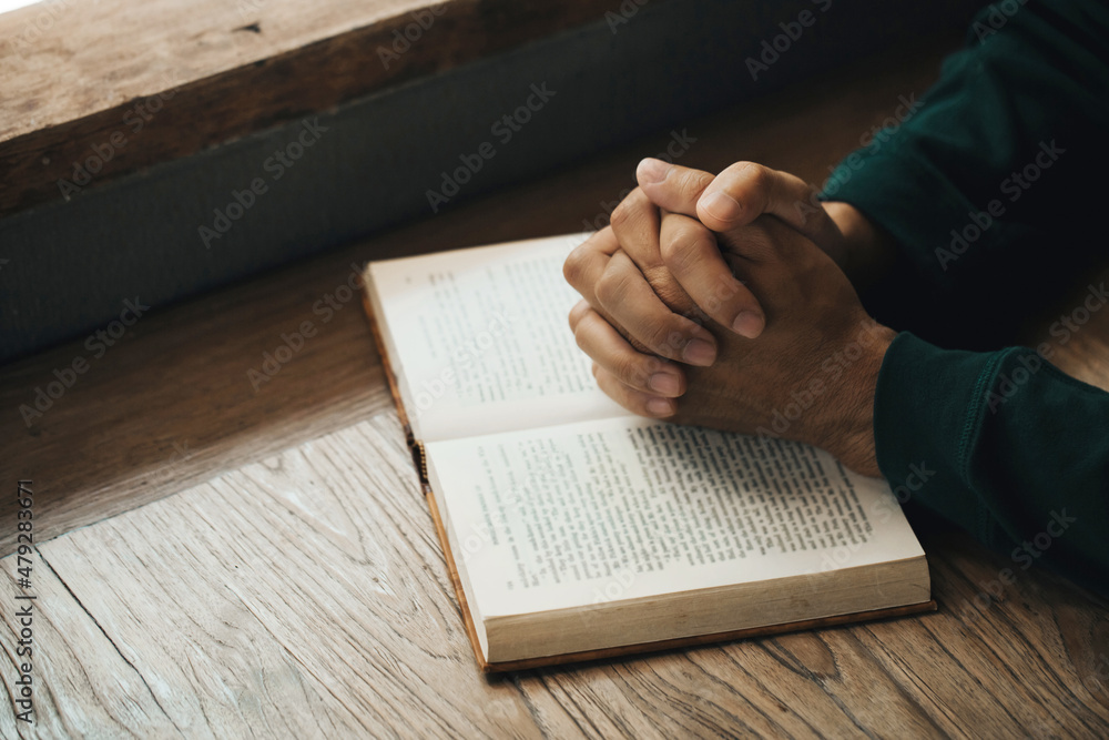 Man hands clasped together on Holy Bible in church concept for faith ...