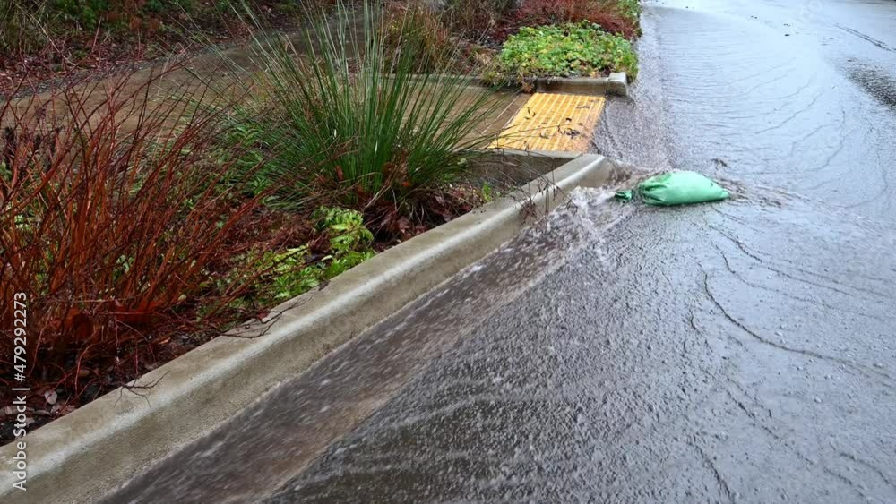 Rainwater flooding down a residential street, sidewalk access ramp, and ...