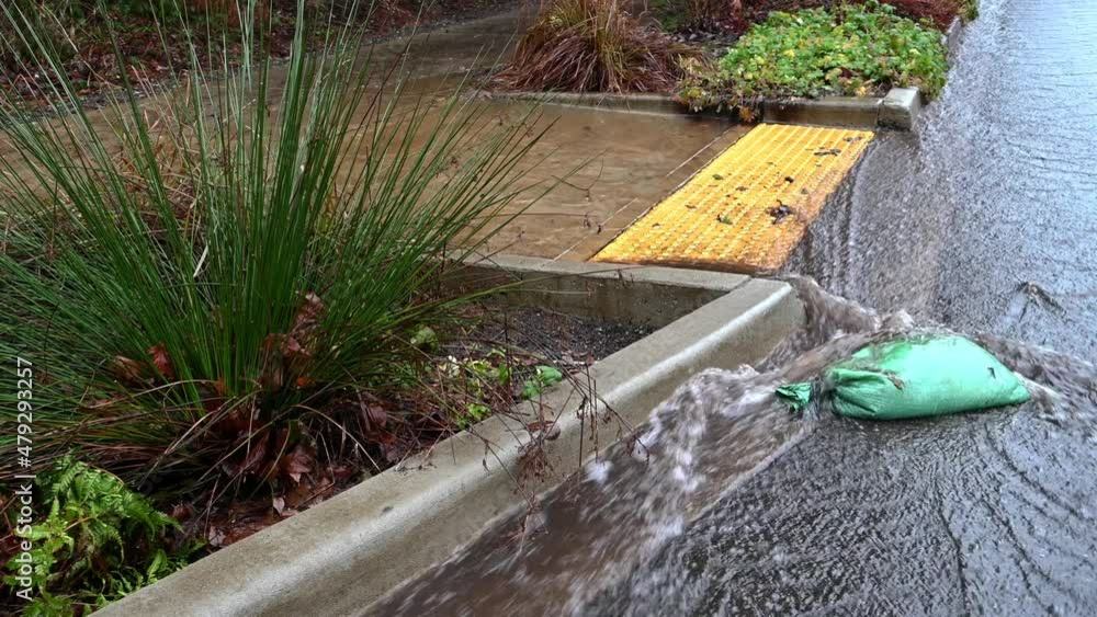 Rainwater flooding down a residential street, sidewalk access ramp, and ...