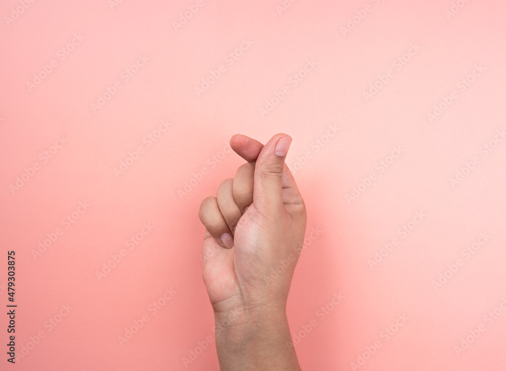 Love and care concept. Hand making a small heart isolated on a pink ...