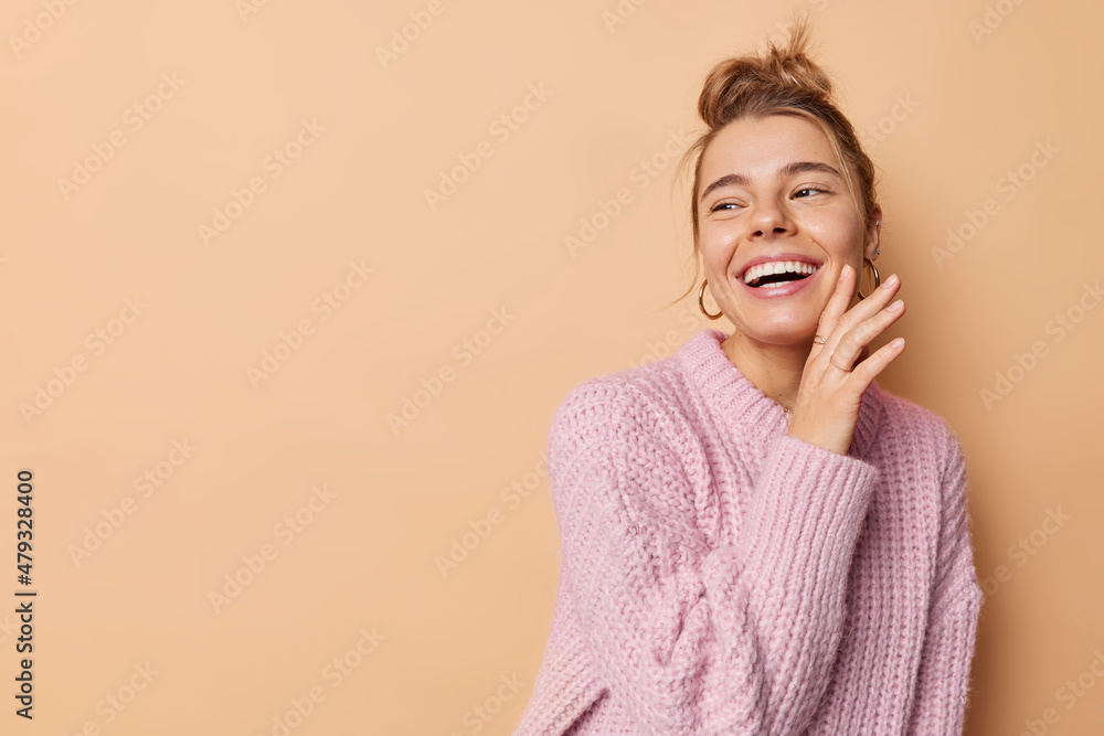 Happy carefree woman with hair gathered in bun touches face gently ...