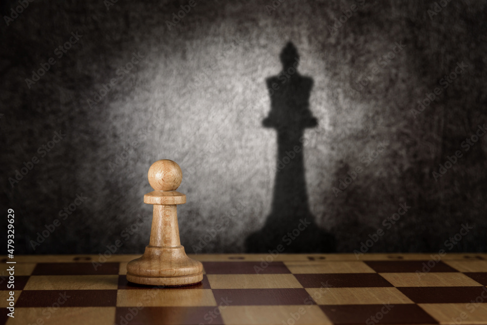a lone pawn on a chessboard casts the queen's shadow on the wall. Stock ...