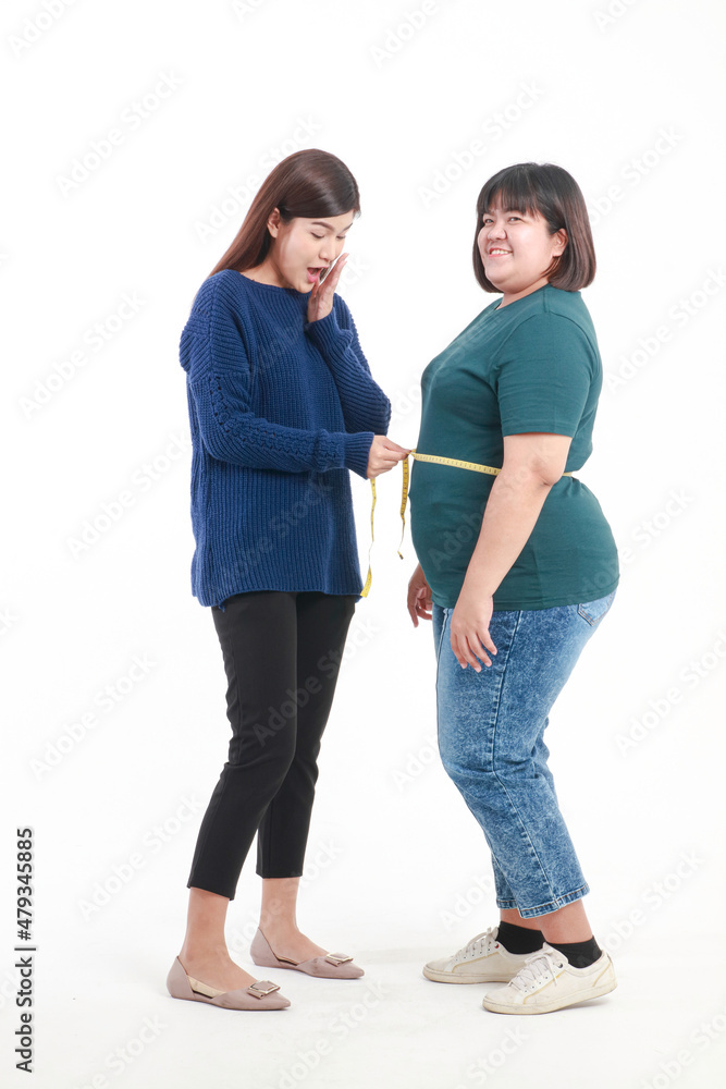 Asian woman holding a tape measure around her waist to measure waist ...