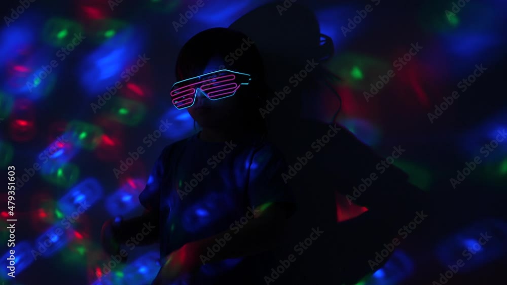 boy child dances at a disco in neon glasses, plays in the metaverse in ...