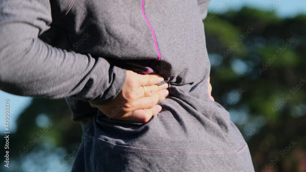 Fitness woman in sportswear touches her injured back while practicing ...