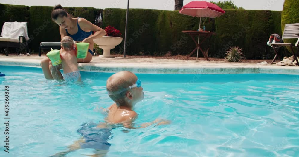 Cheerful family relaxing at swimming pool on summer vacations. Child ...