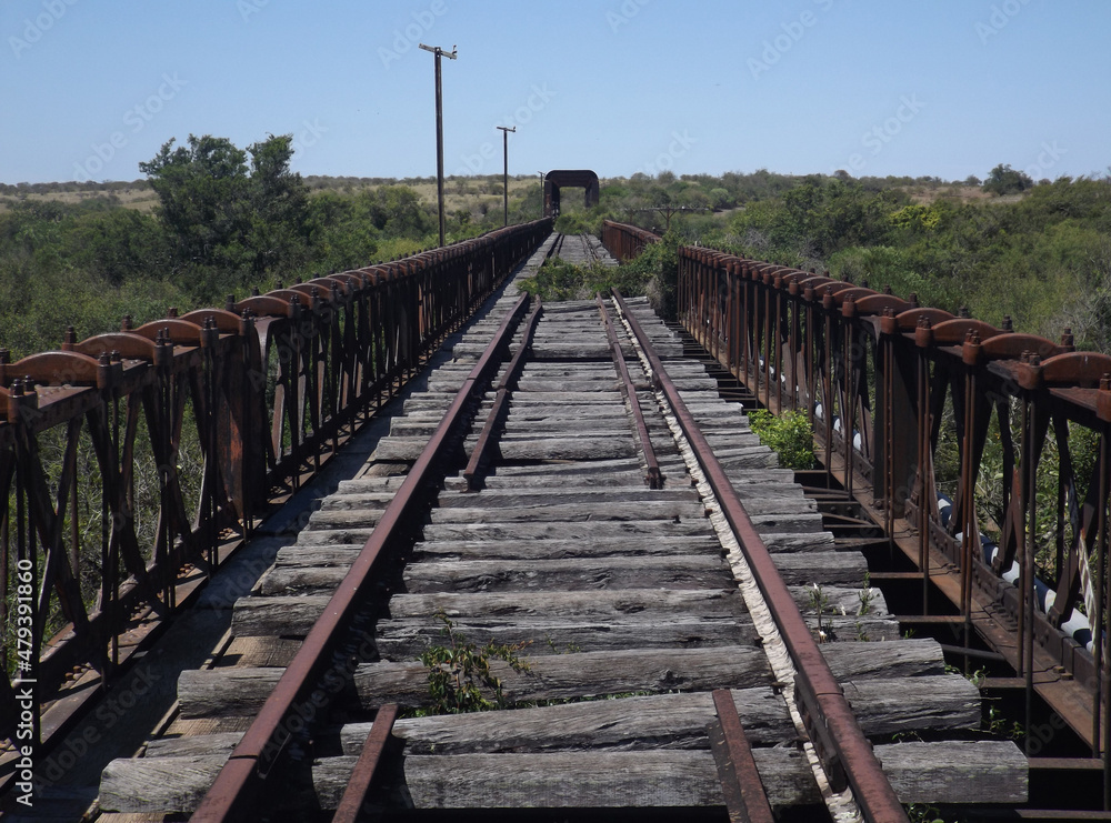 Old abandoned train track passes over an old bridge and continues ...