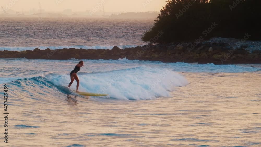 Woman surfs the wave in the ocean on the longboard, she tries to do the ...
