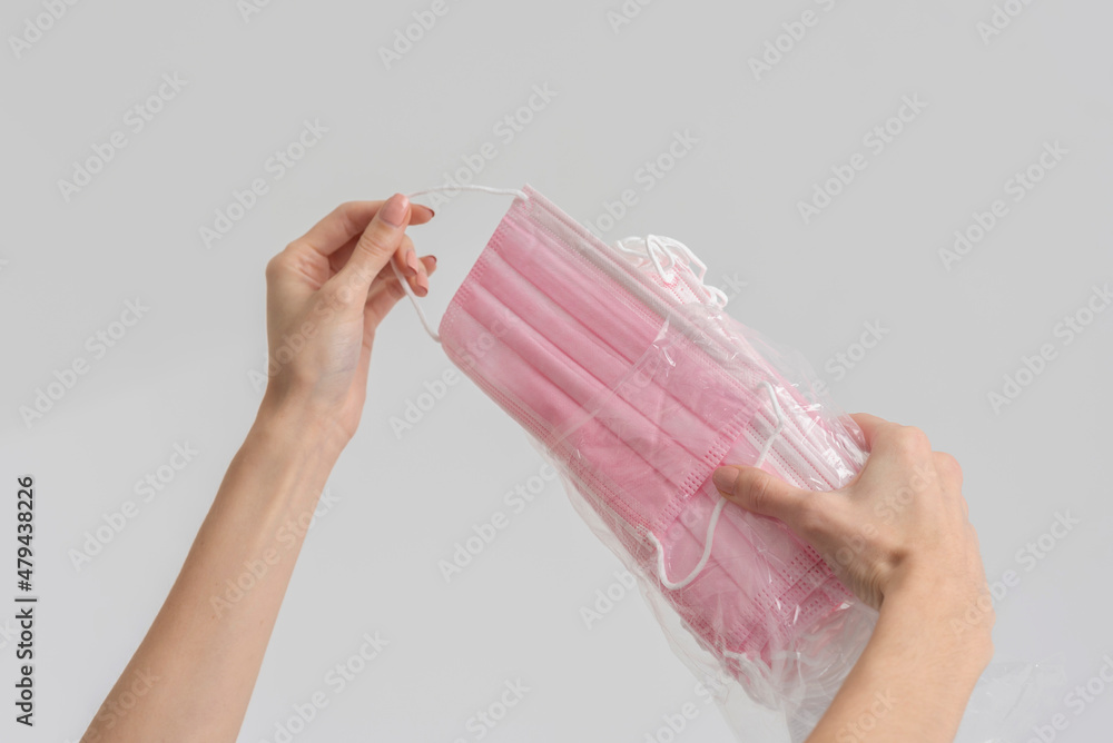 England, UK. 2021. Womans hand removing a pink mask from a transparent ...