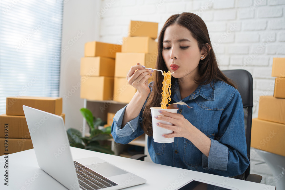 Asian businesswoman eating instant noodles after hard work. She is ...