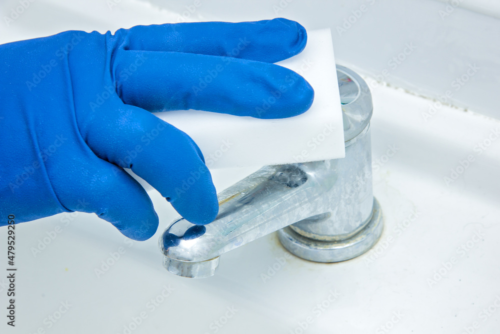 Cleaning the bathroom with melamine sponge. A gloved hand holds a ...