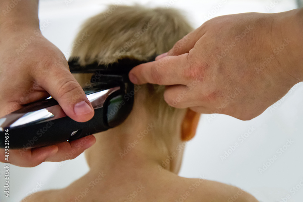 Kid boy with blond hairs getting his first haircut with razor blade in ...