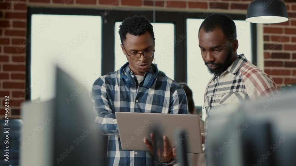 Coders talking about algorithms holding laptop pointing at sorce code on screen standing in ...