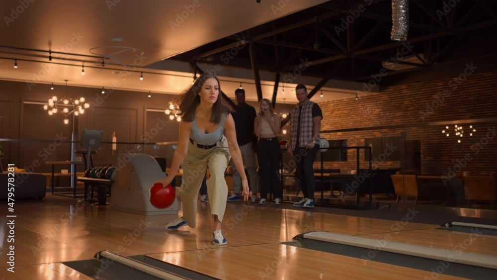A woman makes a throw in a bowling club and enjoys emotionally knocking ...