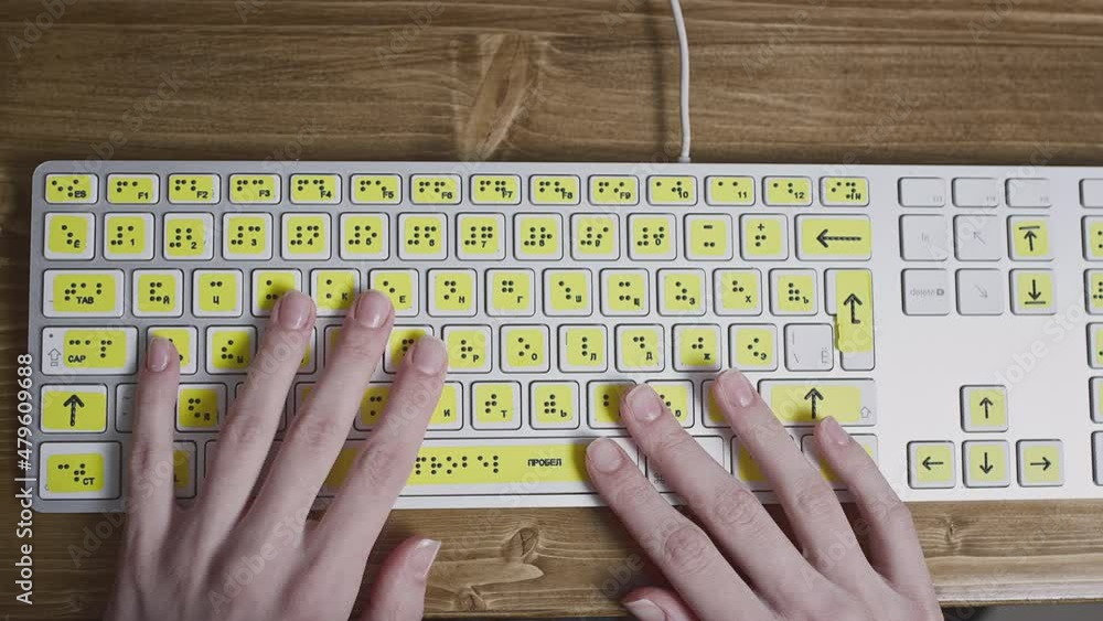Close-up of a computer keyboard with braille. A blind girl is typing ...