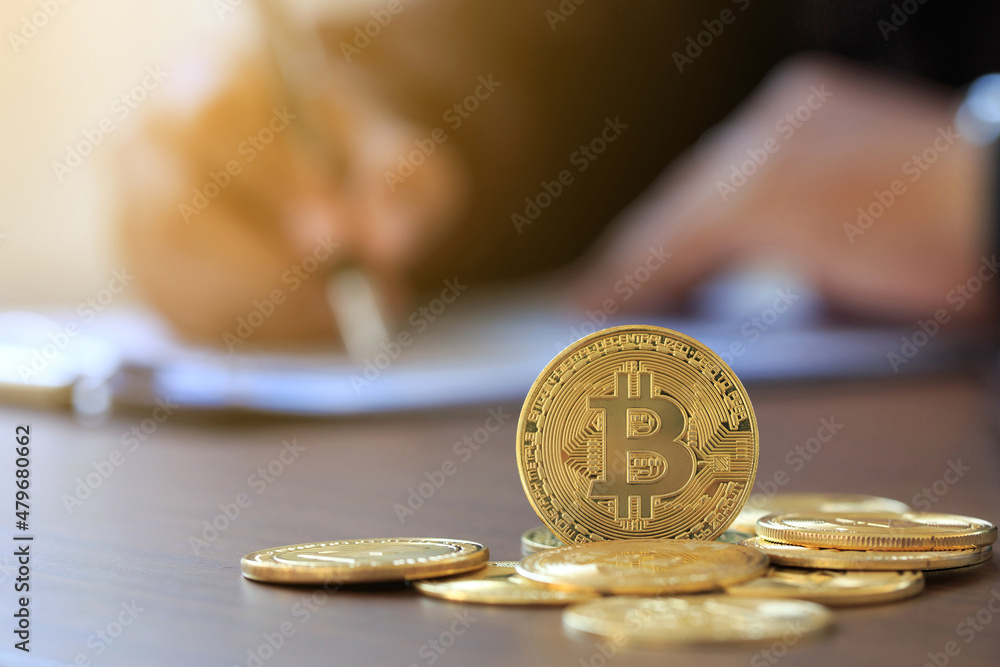 Bitcoin on wooden table and man signing individual income tax return ...