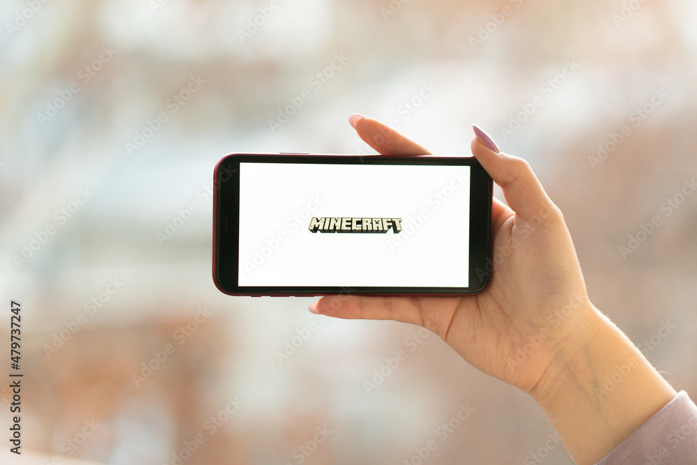 Hands holding a smartphone with Minecraft Pocket Edition game on ...